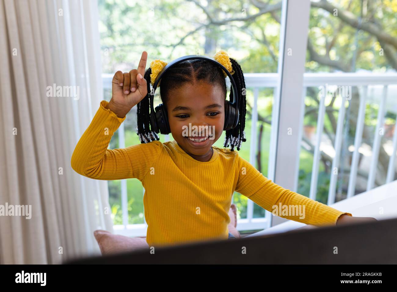 African american smiling girl raising hand while studying online over ...