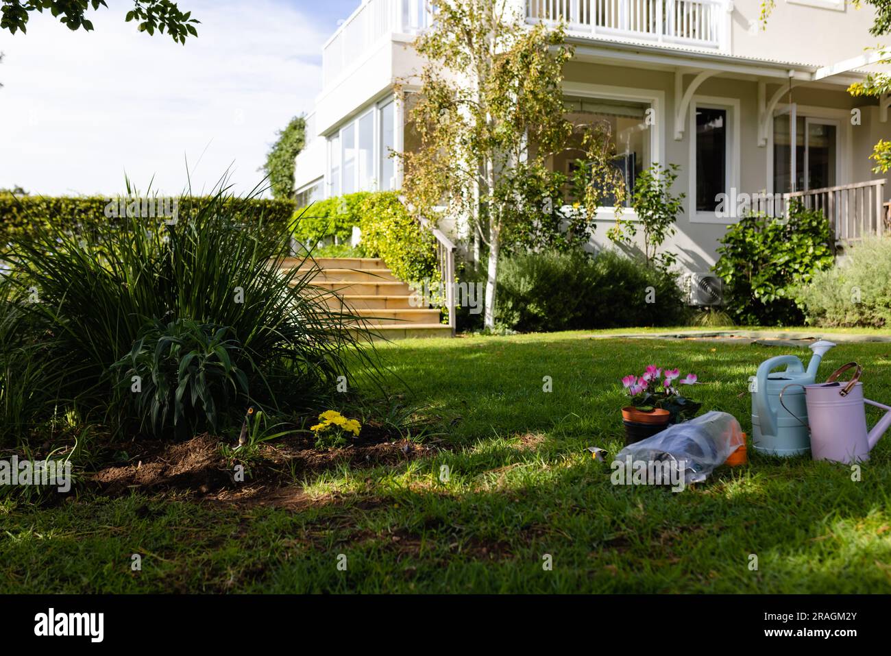 Watering cans with flower pots and dirt on grassy land in yard outside ...