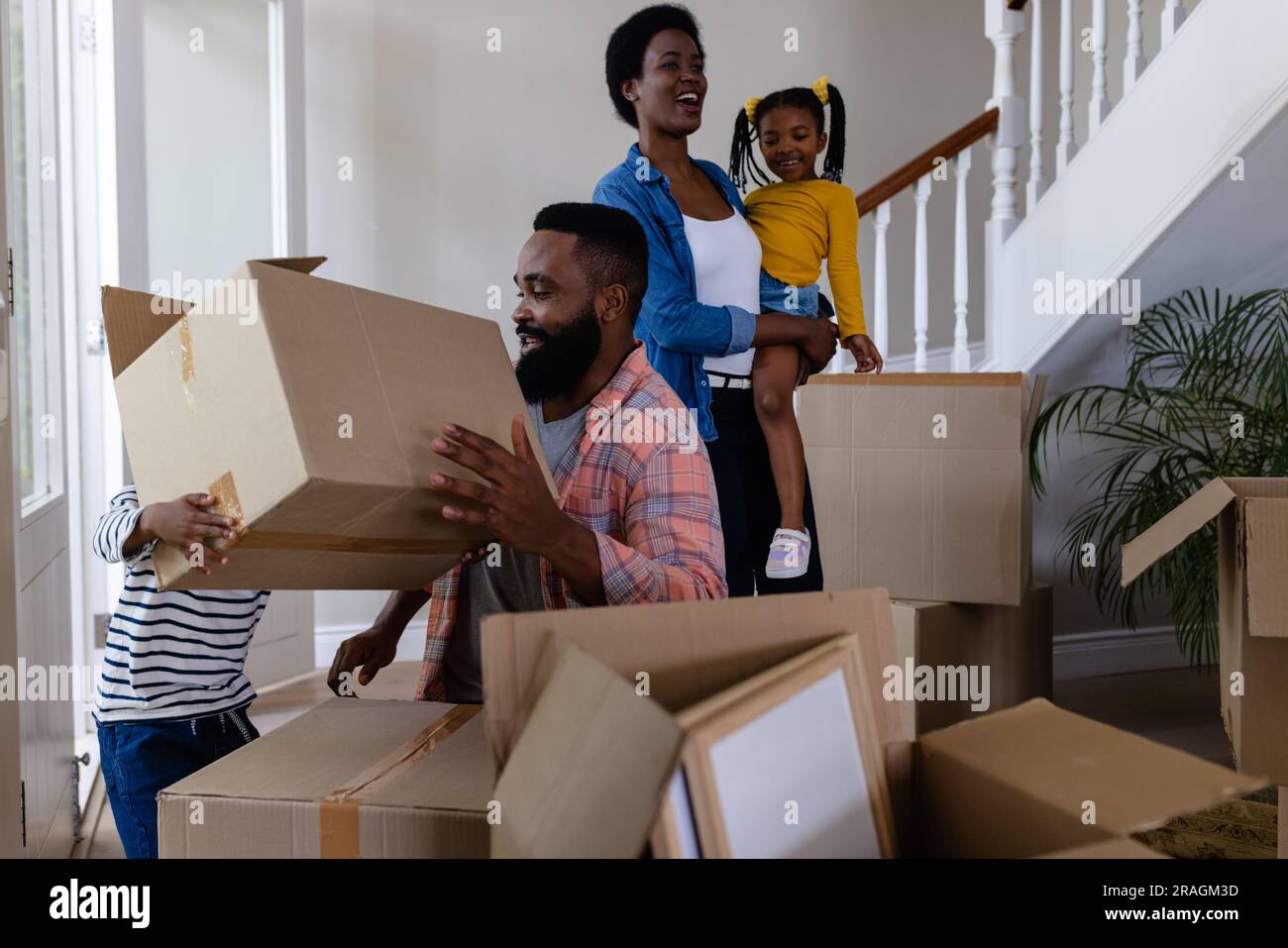 African american parents and children arranging cardboard boxes in new ...