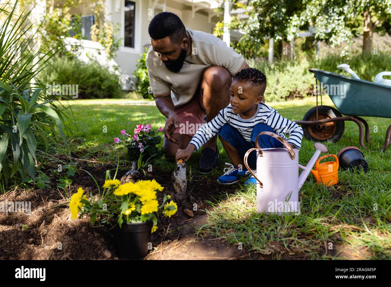 African american father assisting son in digging dirt for planting ...
