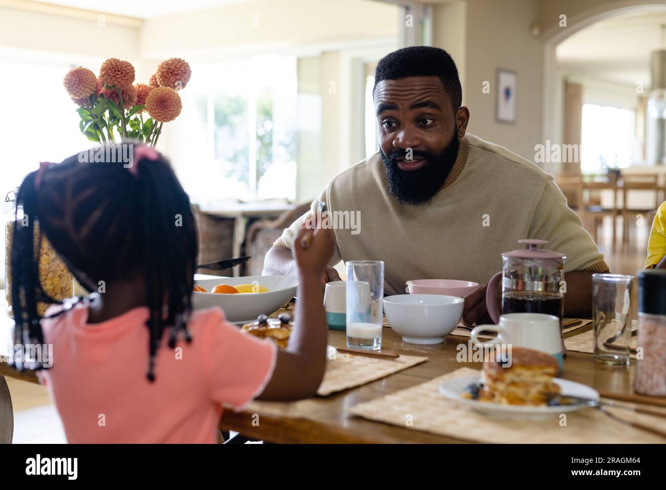 African american father talking with daughter while having breakfast at ...