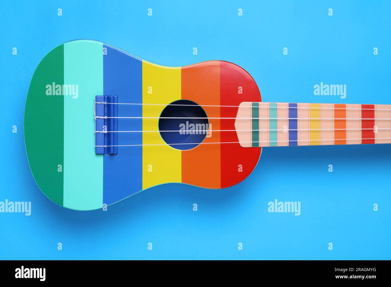 Colorful ukulele on light blue background, top view. String musical ...