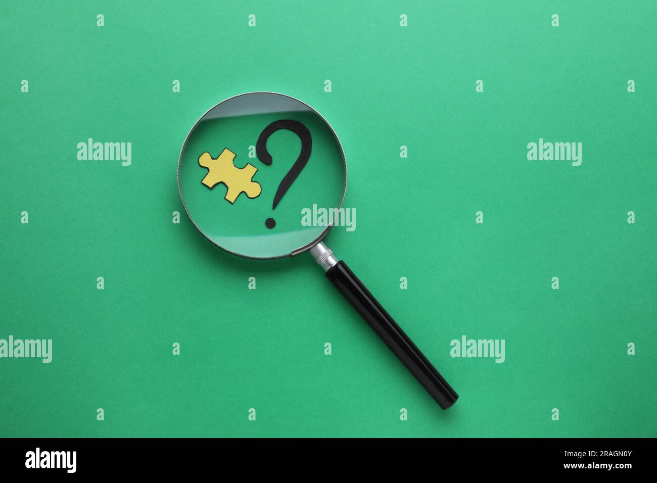 Magnifying glass over paper puzzle and question mark on green ...