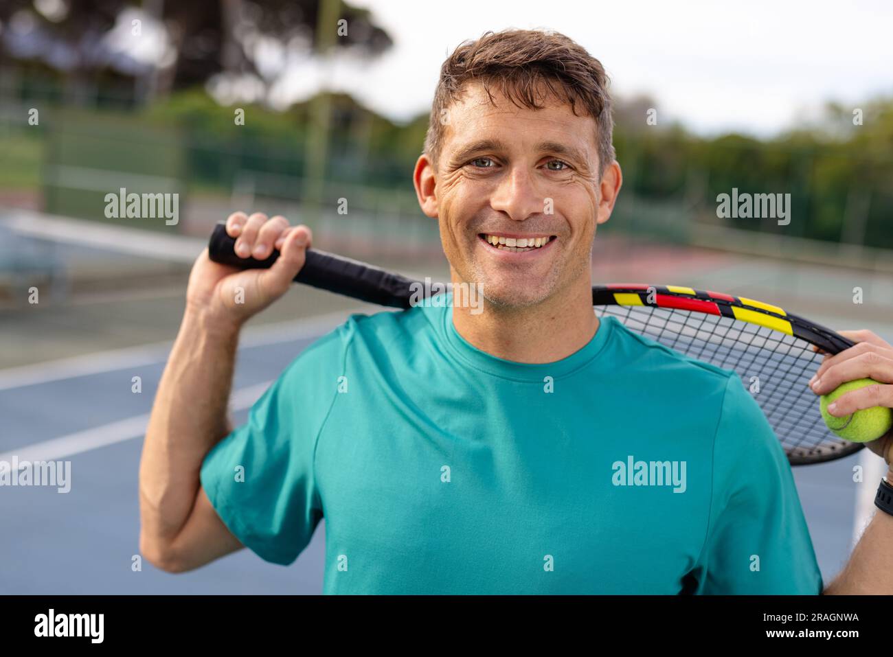 Portrait of happy caucasian male tennis player holding tennis racket ...