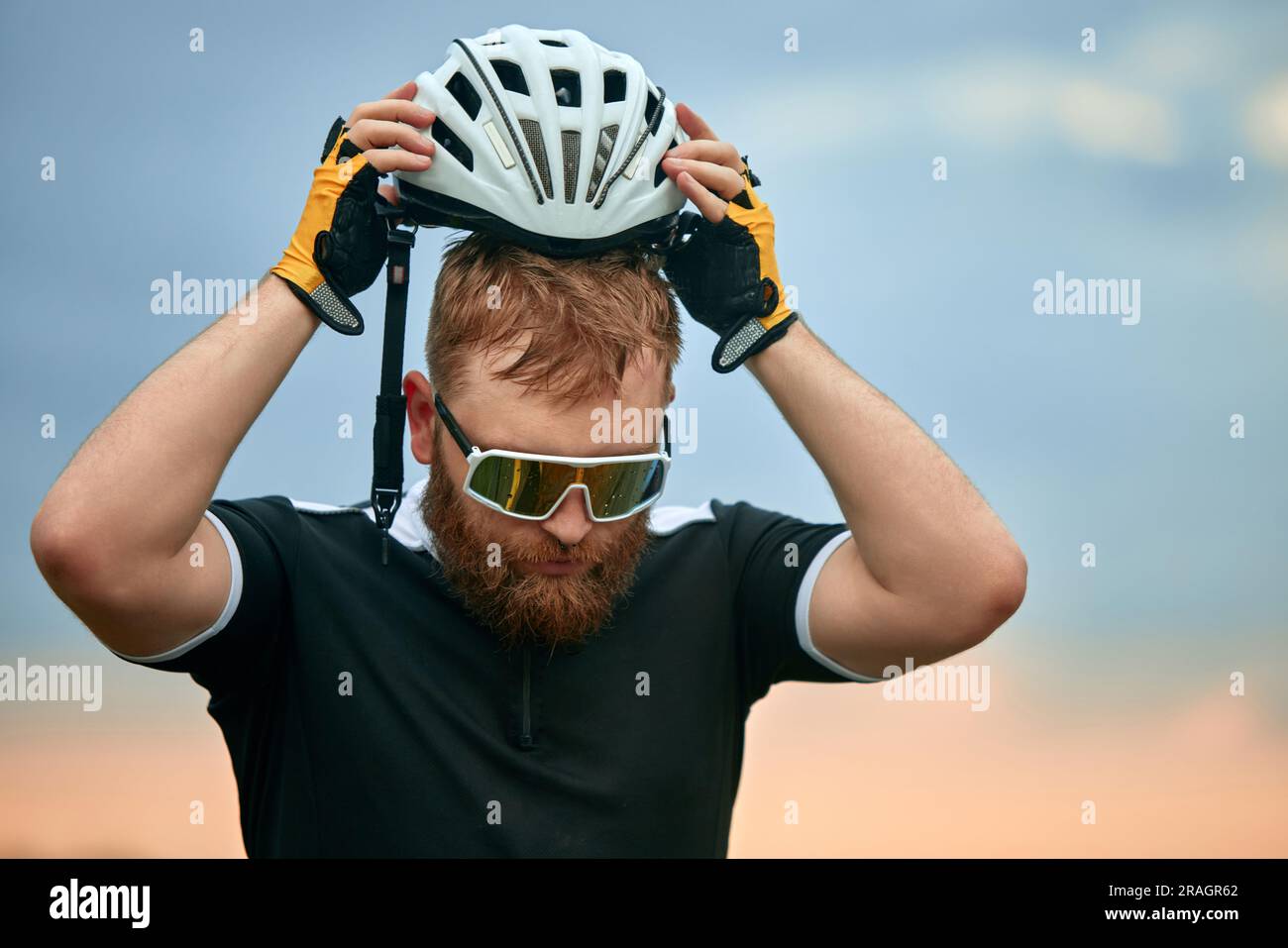 Young bearded man, bike rider in gradient sport glasses, taking off ...