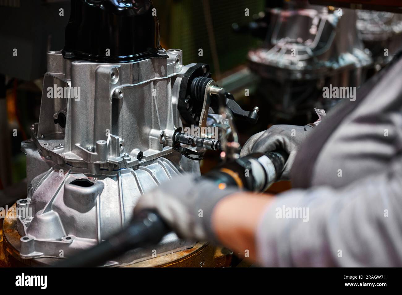 Worker connects car engine gearbox details on shop conveyor Stock Photo ...