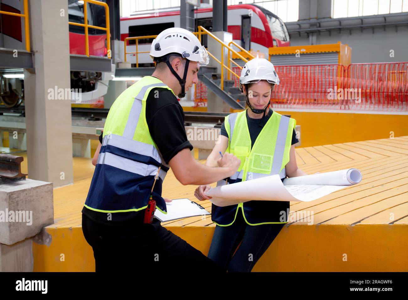 Young caucasian engineer man and woman or worker looking blueprint and ...