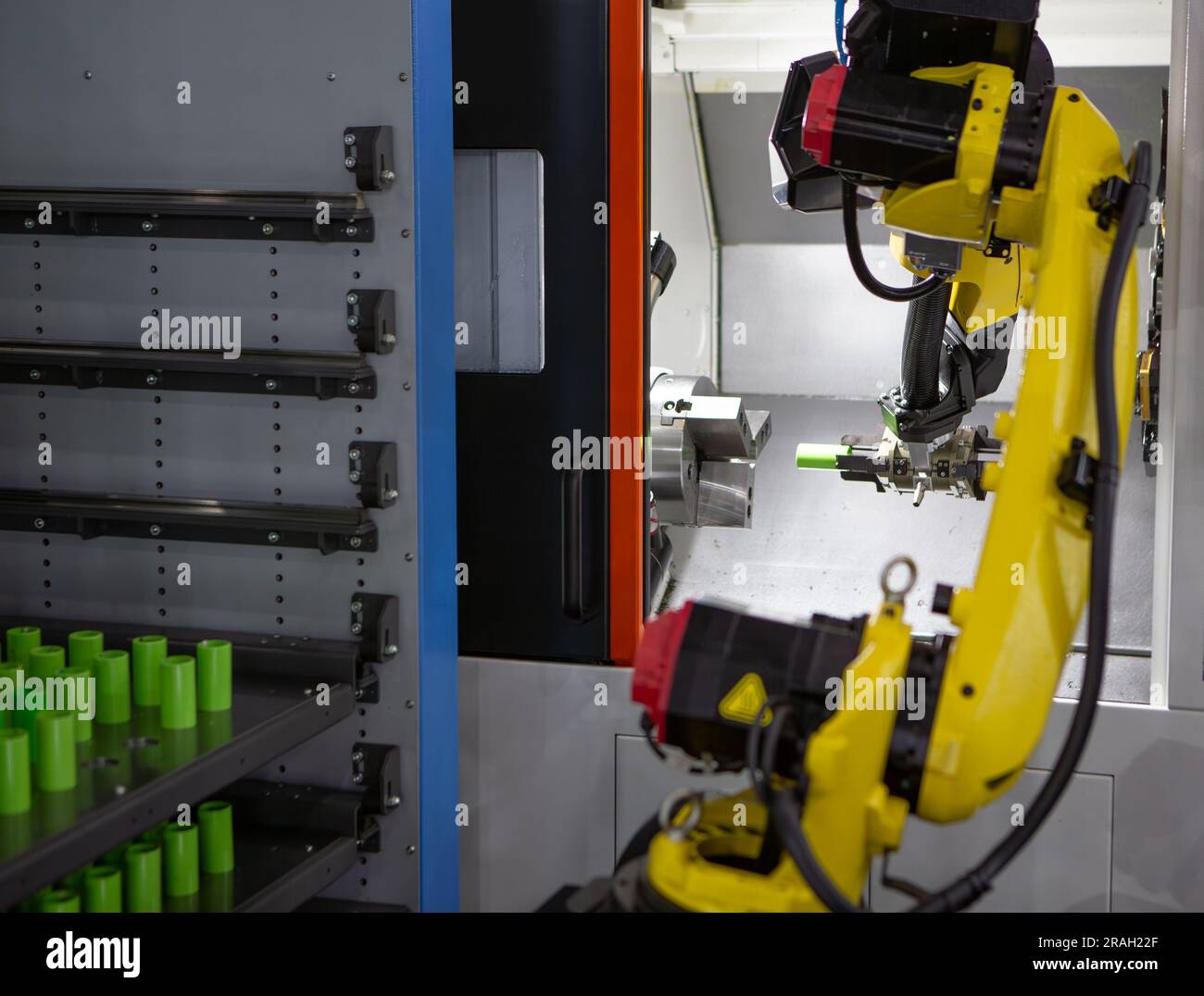 Automated manufacturing process. Robot arm loading workpieces on CNC lathe machine Stock Photo ...