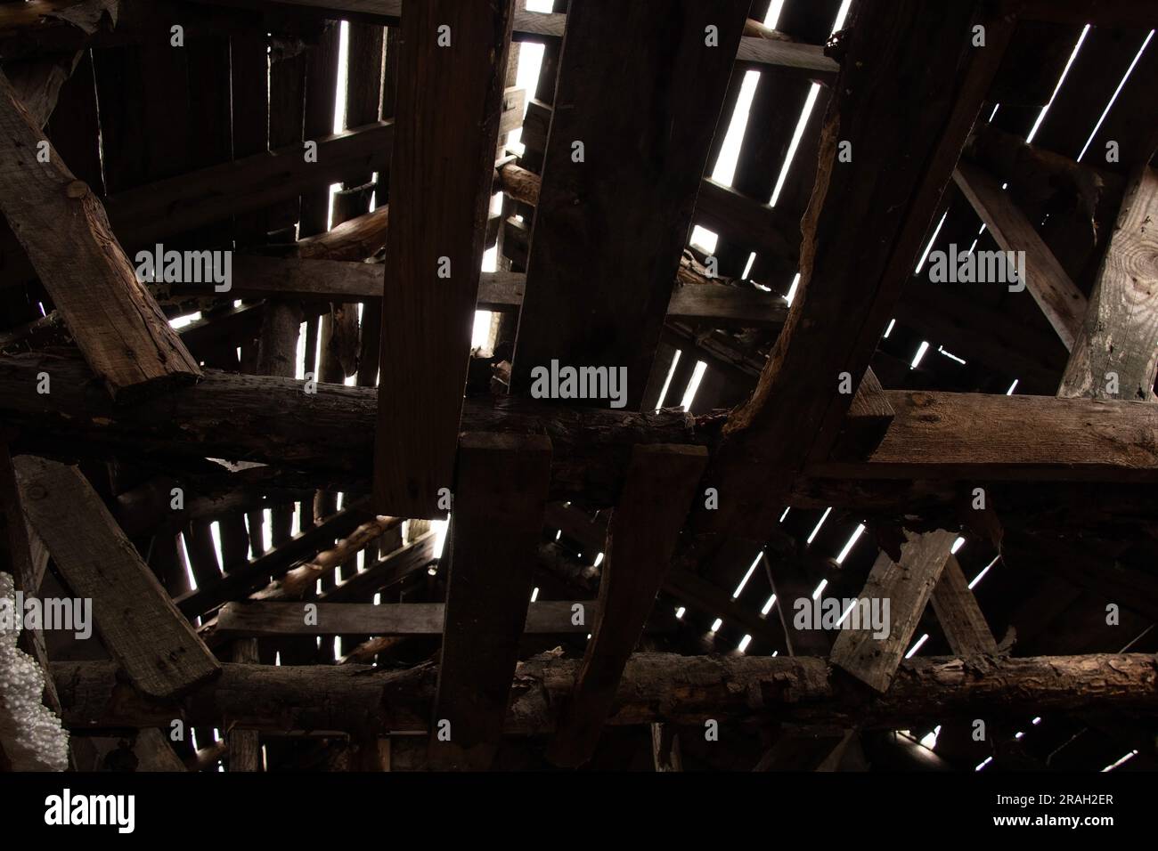 an attic made of wooden planks and beams with cracks from which ...