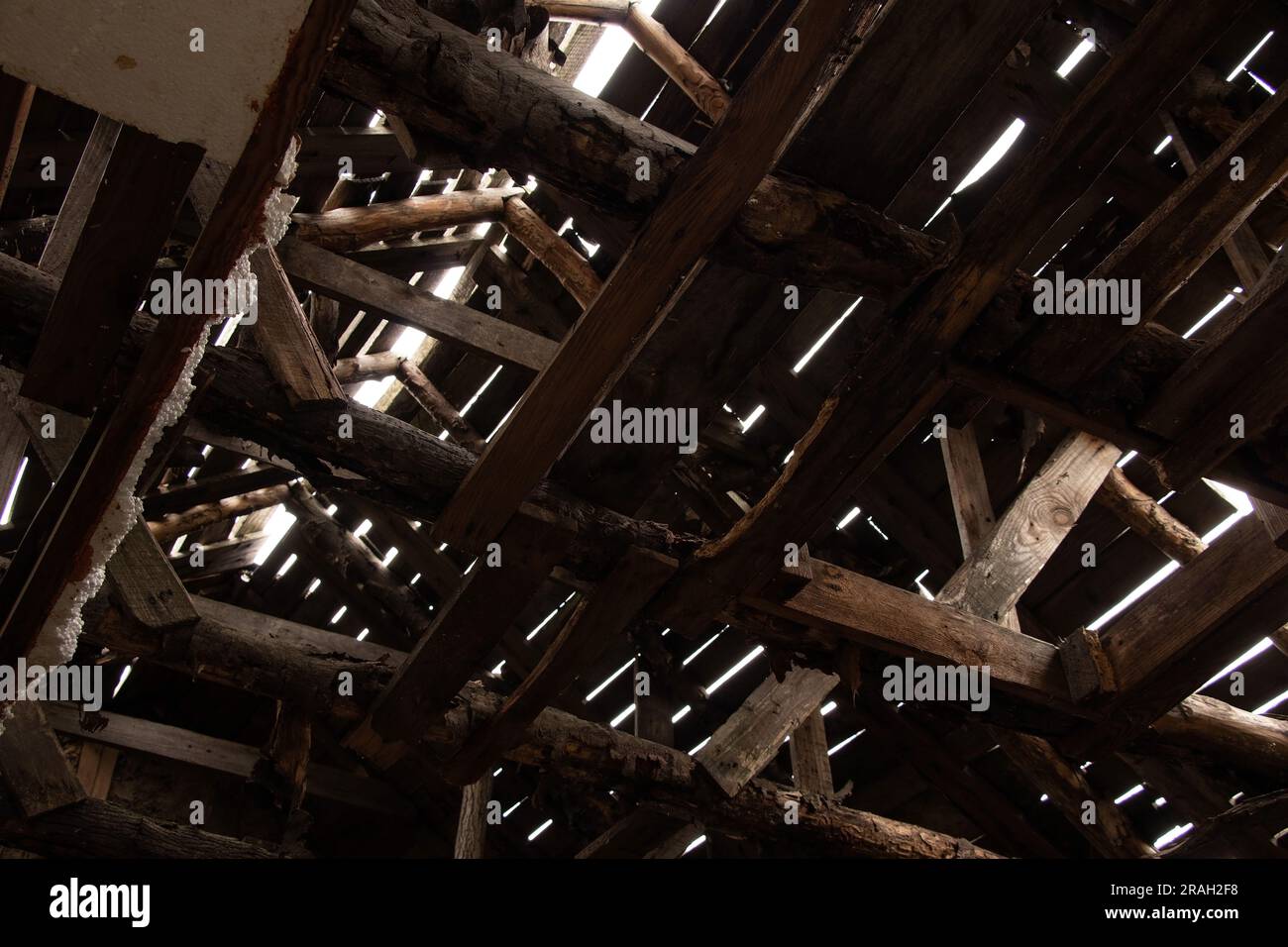 an attic made of wooden planks and beams with cracks from which ...