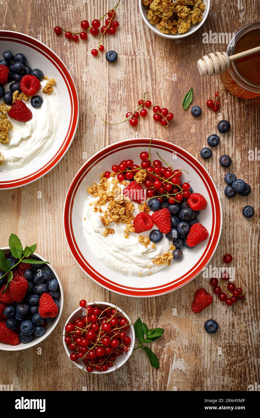 Yogurt with berries on wooden background. White plain greek yogurt with ...