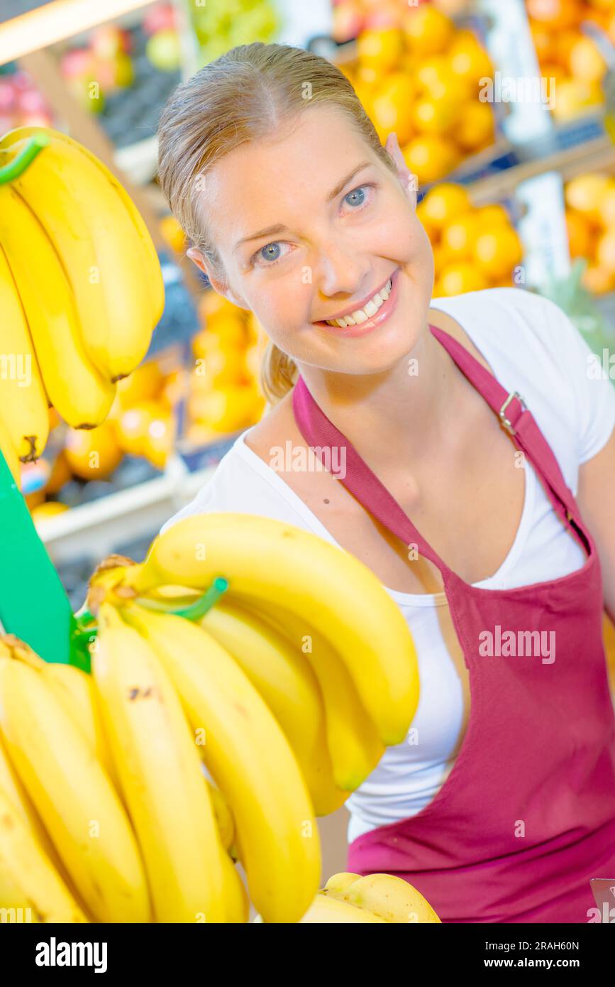 Shop worker stood next to display of bananas Stock Photo - Alamy