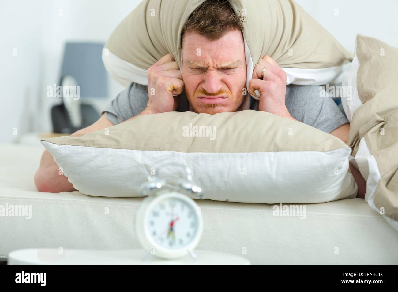 angry man lying in the bed with pillow on head Stock Photo - Alamy