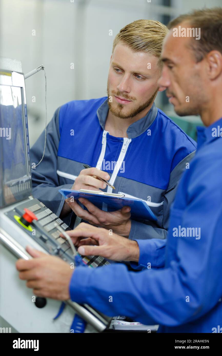 portrait of two men wearing overalls operating modern machines Stock ...