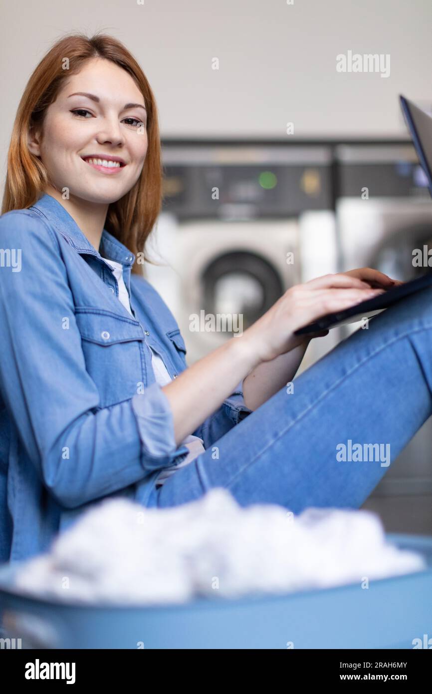 young business woman with a pc while doing the laundry Stock Photo - Alamy