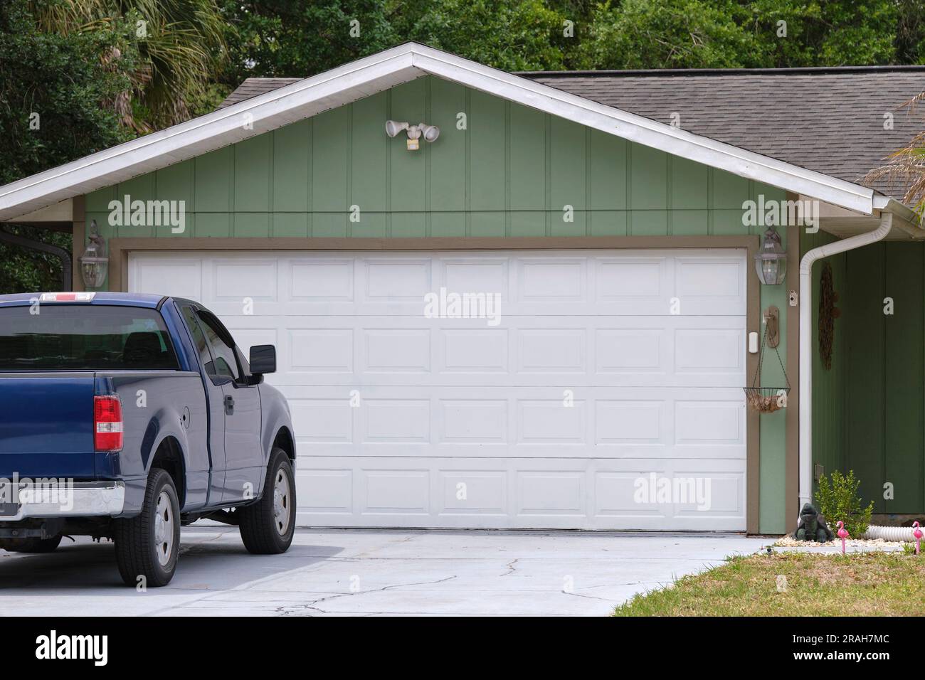 Vehicle parked in front of wide garage double door on paved driveway of ...