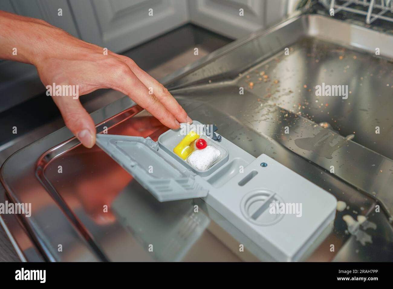 Person putting dishwasher tablet into dirty dishwasher. Dishwashing ...