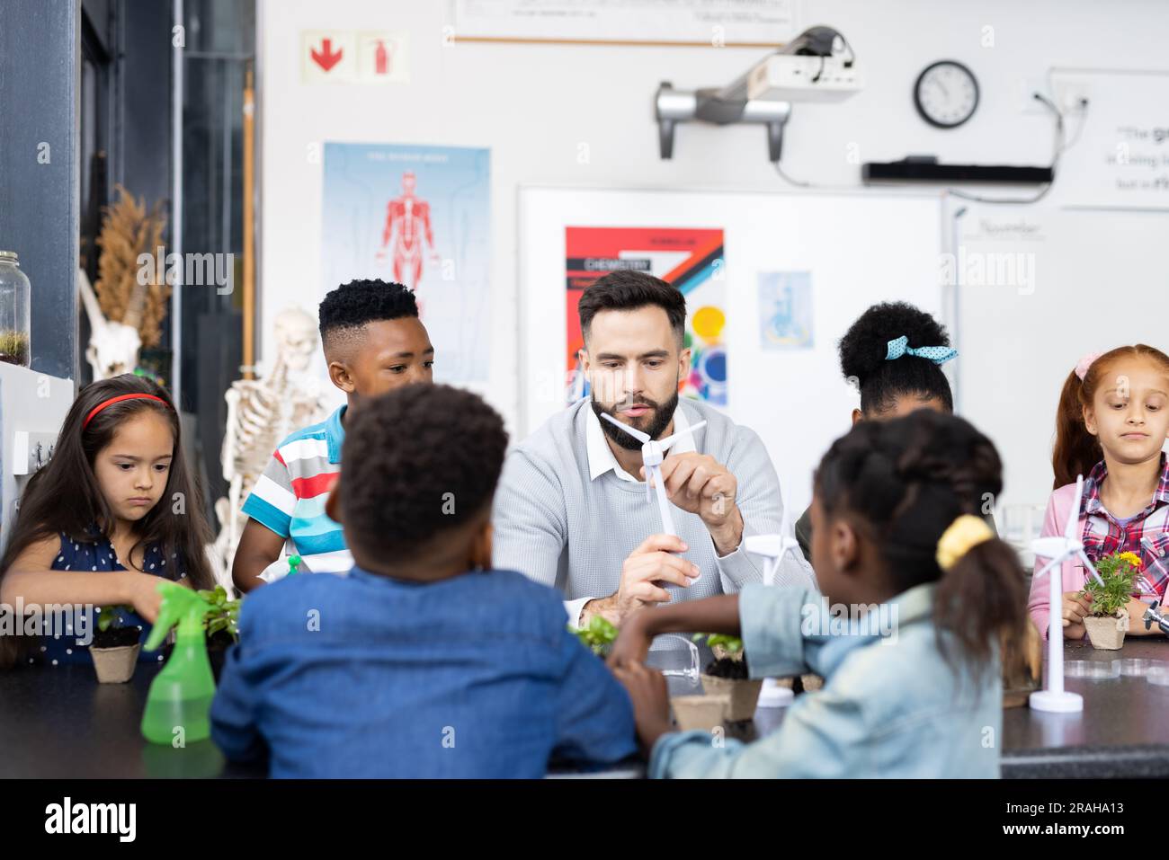 Diverse elementary schoolchildren and male teacher studying wind ...