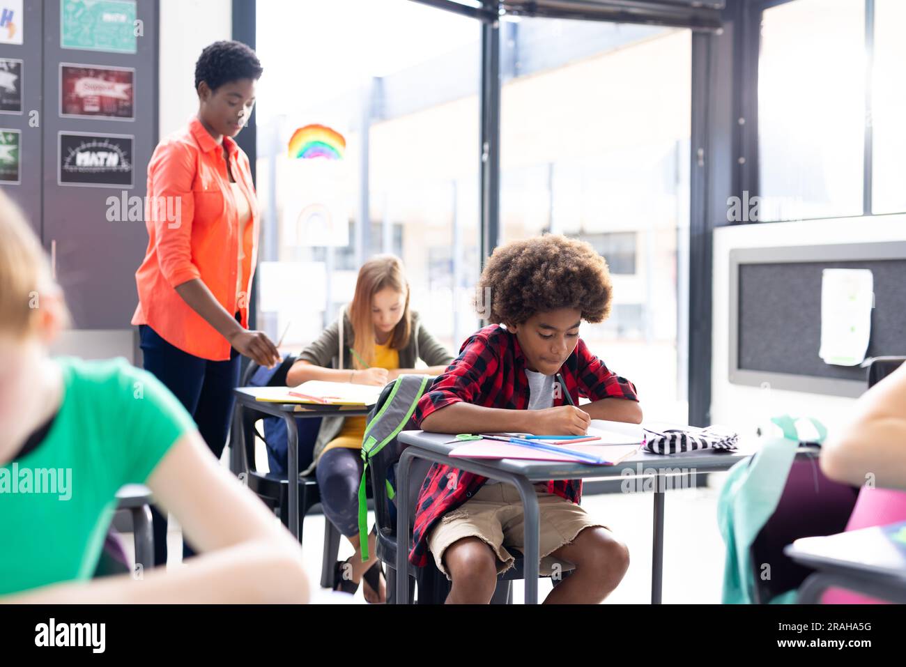 African american female teacher and diverse pupils at work in classroom ...