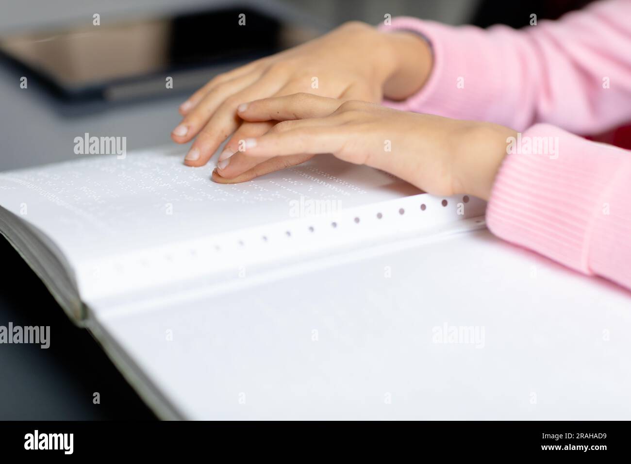 Hands of blind, biracial schoolgirl at desk reading braille in class ...
