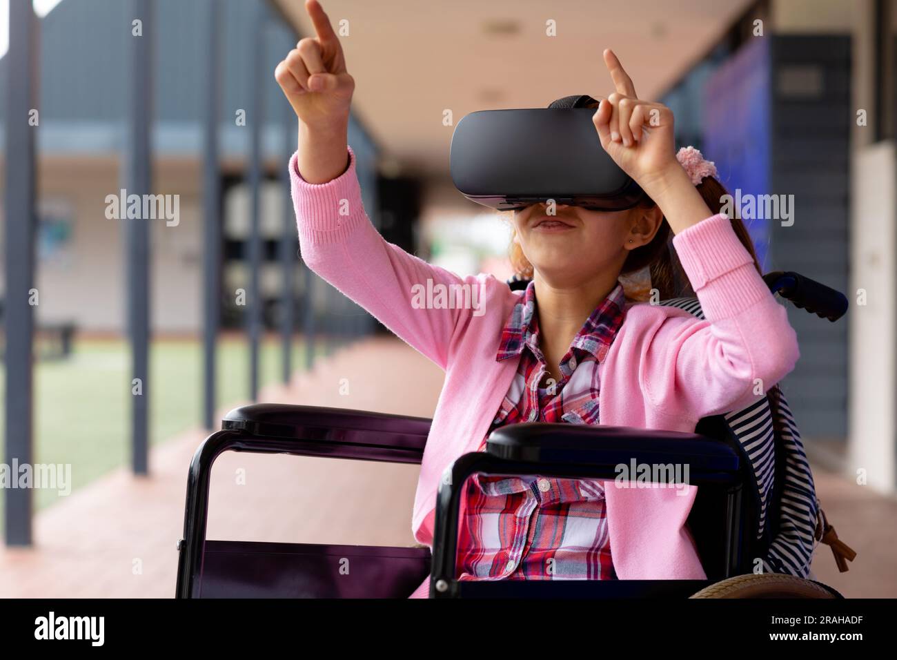 Biracial girl in wheelchair, using vr headset, pointing fingers, in ...