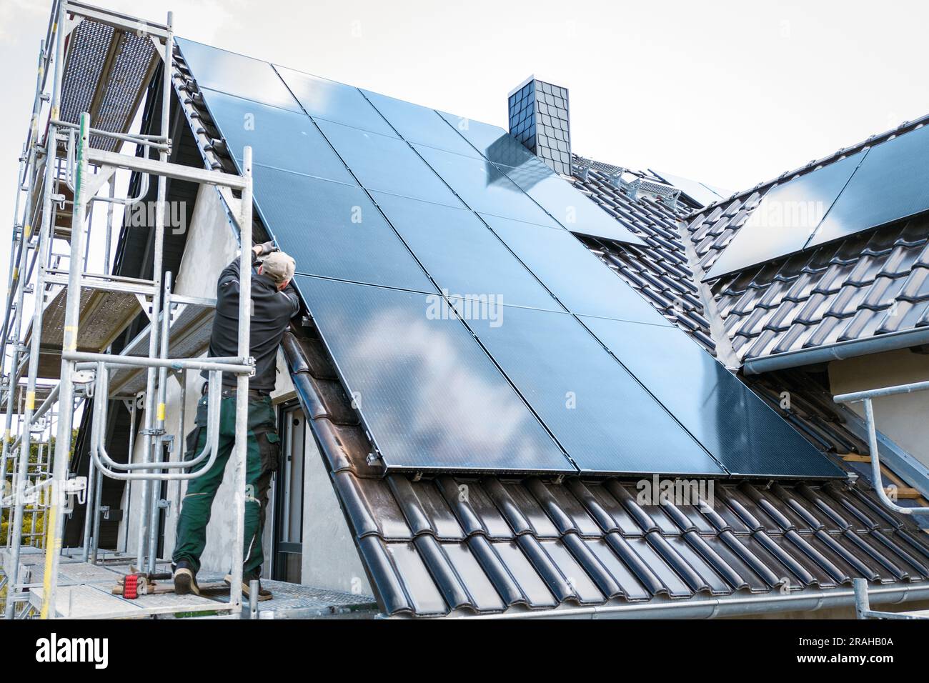 Person installing solar panels at the construction site of a house ...