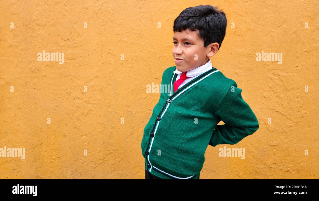9-year-old dark-skinned Latino boy in school uniform suffers from back ...
