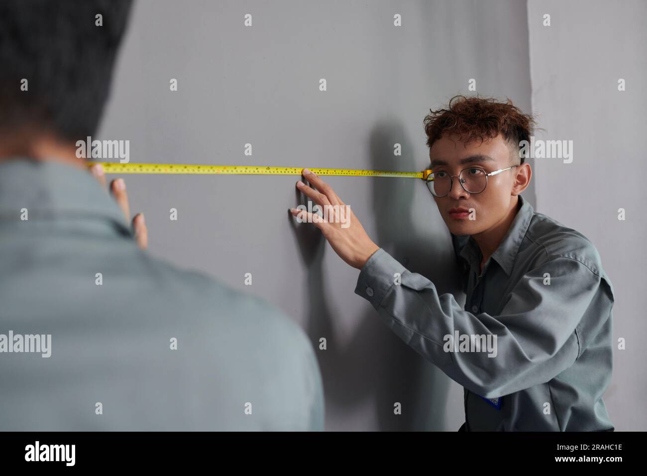 Construction workers measuring wall with tape measure Stock Photo - Alamy