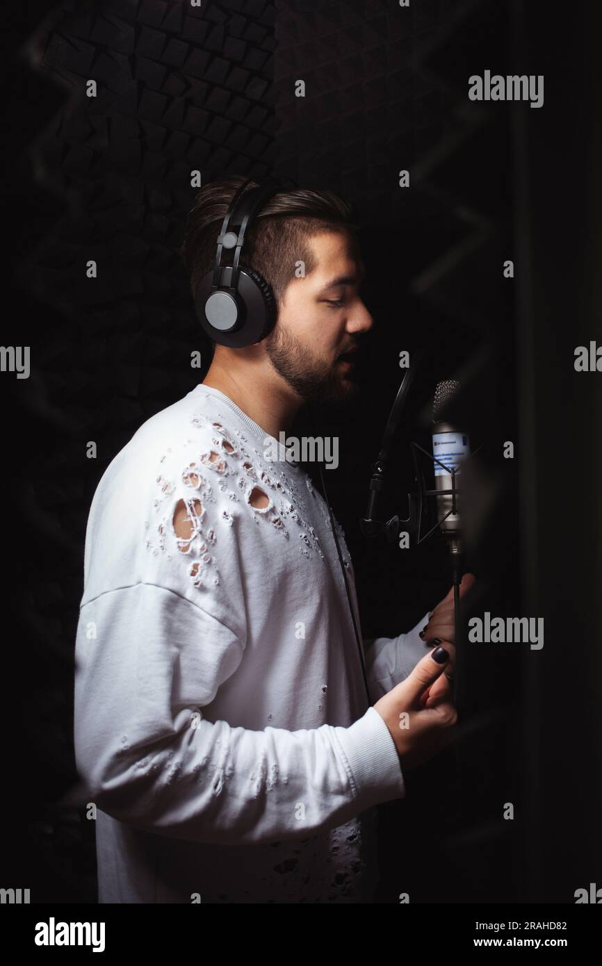 man sings into microphone, professional recording studio, headphones ...