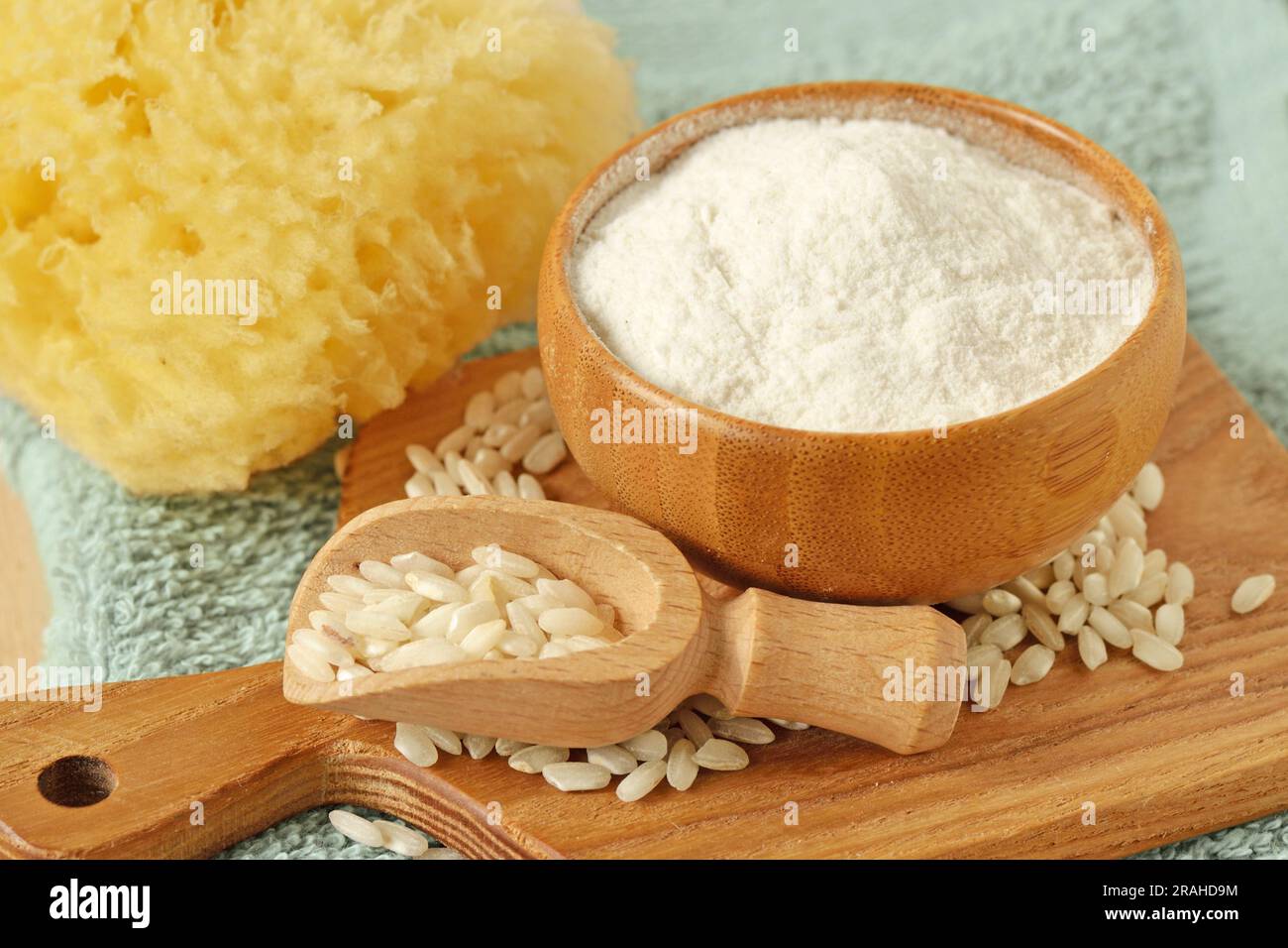 Rice flour in wooden bowl and grains of rice on wooden chopping board ...