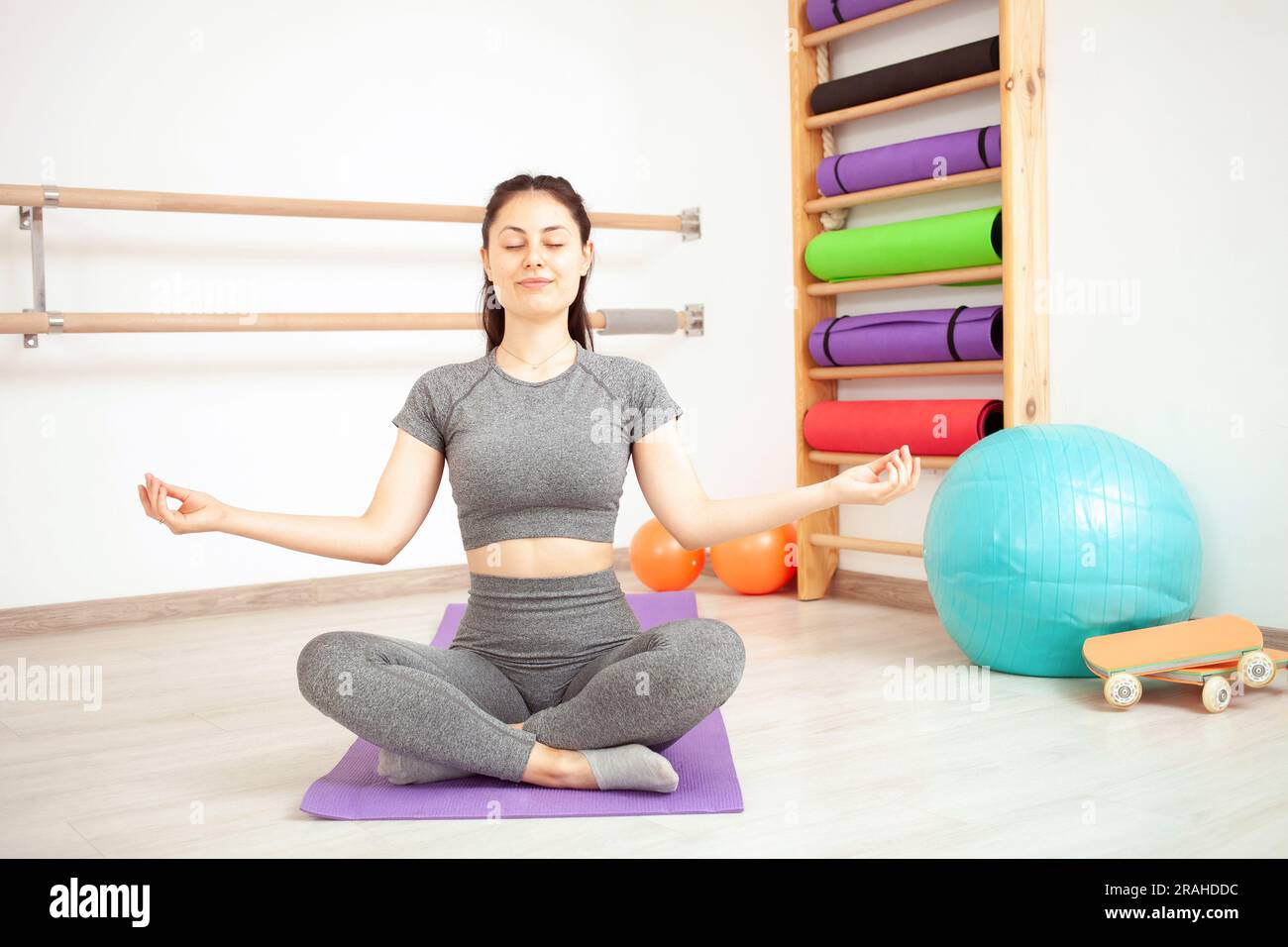 girl performs exercises for yoga in gym, gymnastics. Sits in lotus ...