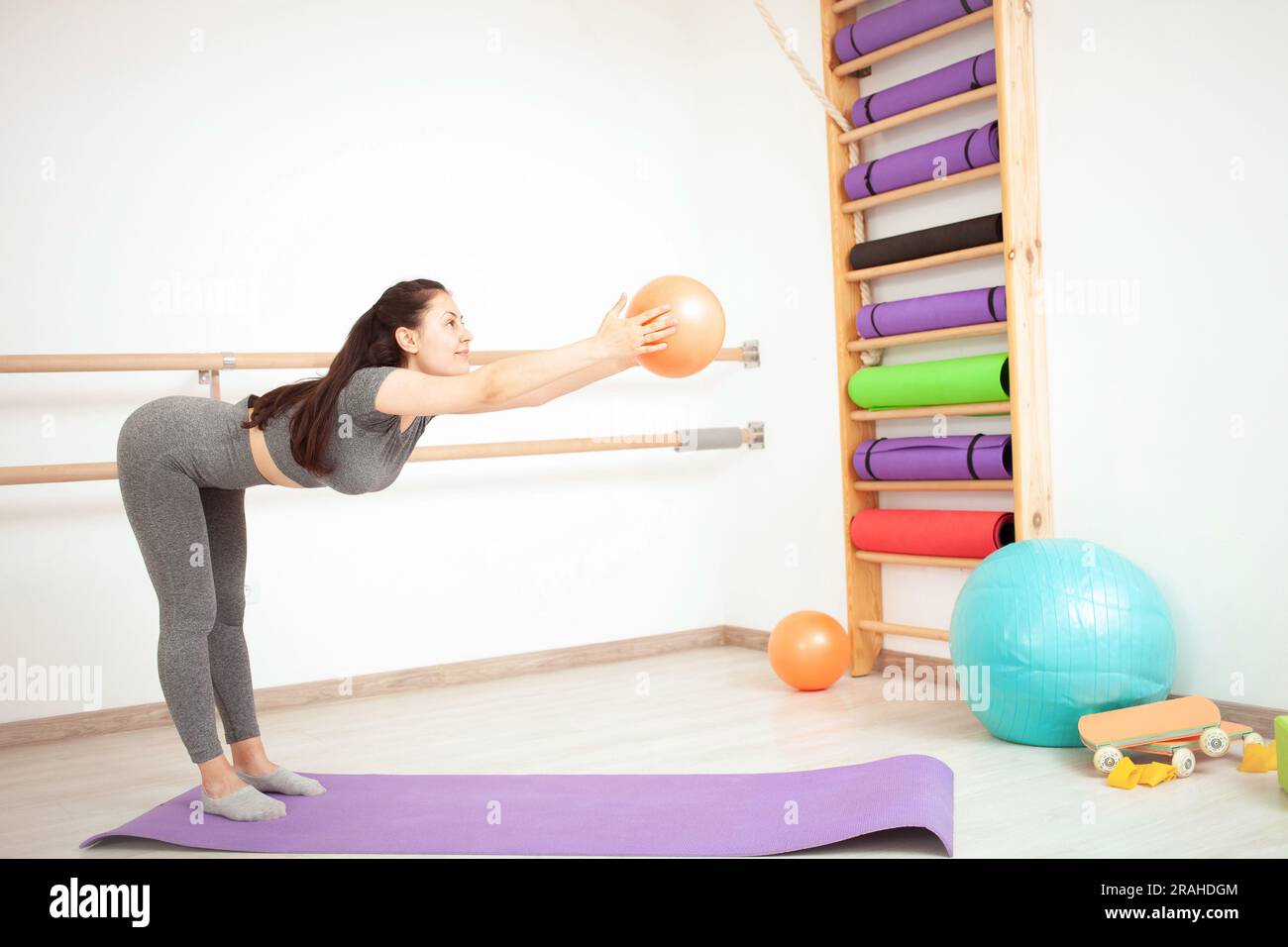 young woman is doing gymnastics in gym. Healthy lifestyle. purple mat ...