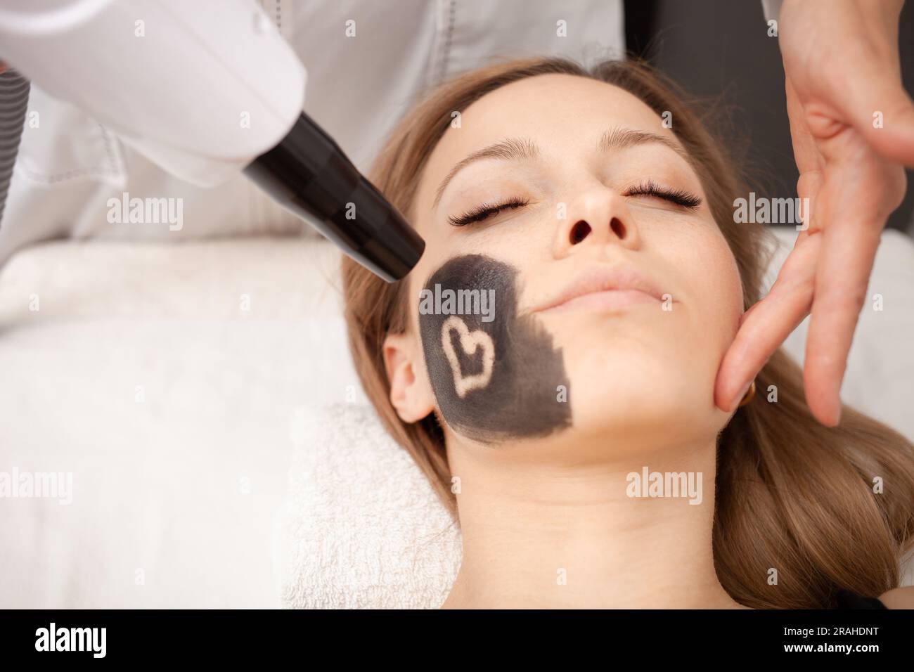 cosmetologist does procedure of carbon peeling of face. Black mask ...