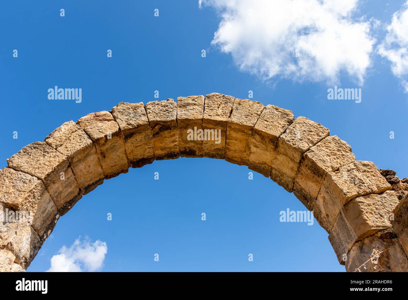 Low-angle view of a Roman arch against a blue sky in the ancient town ...