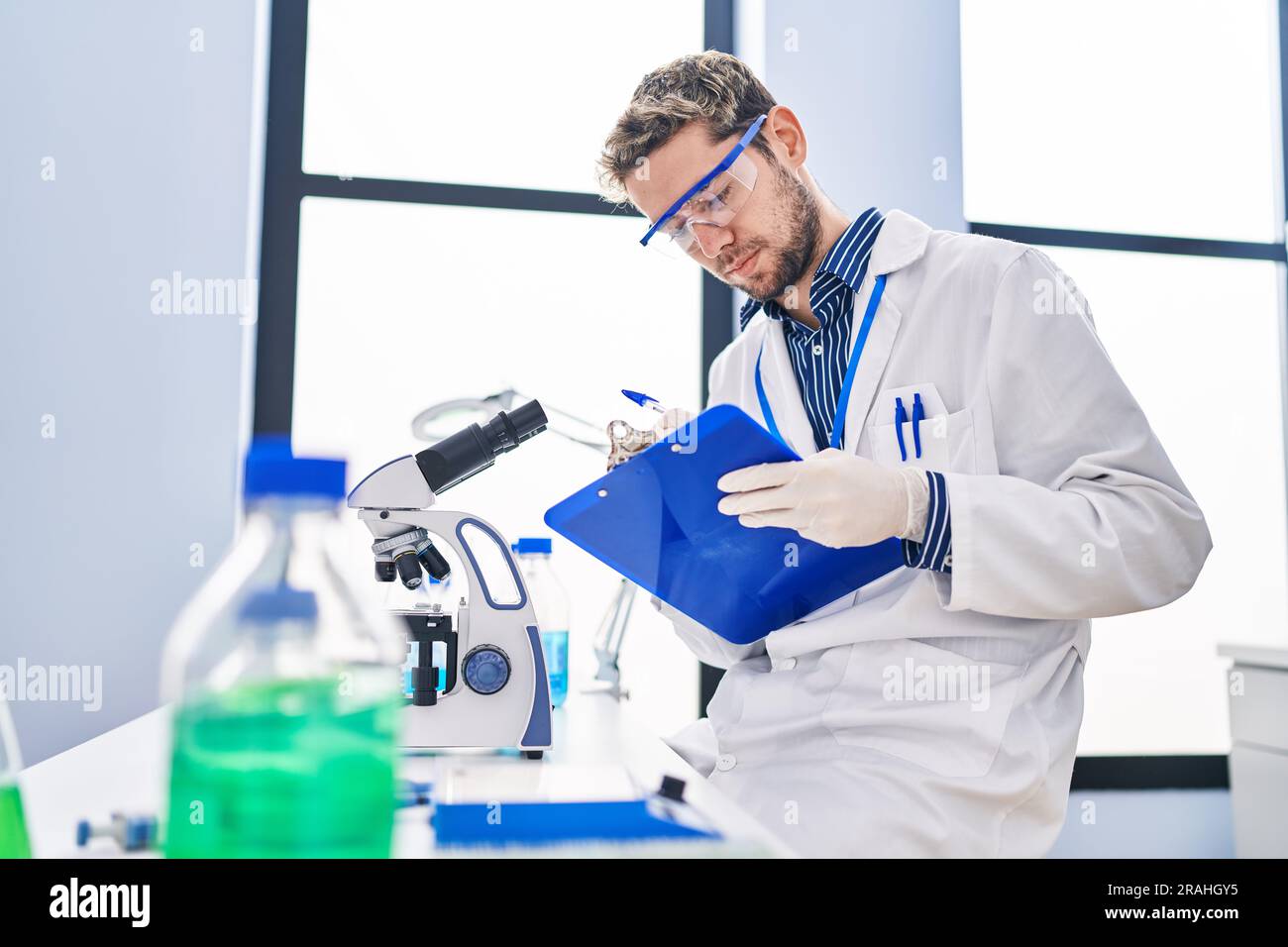 Young man scientist writing report working at laboratory Stock Photo ...