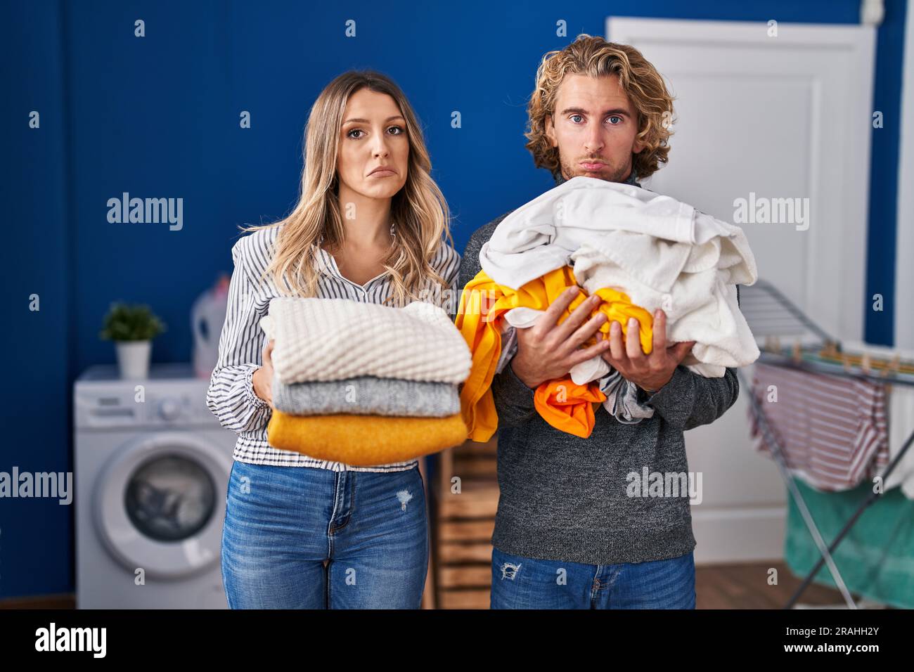 Young couple doing laundry depressed and worry for distress, crying ...
