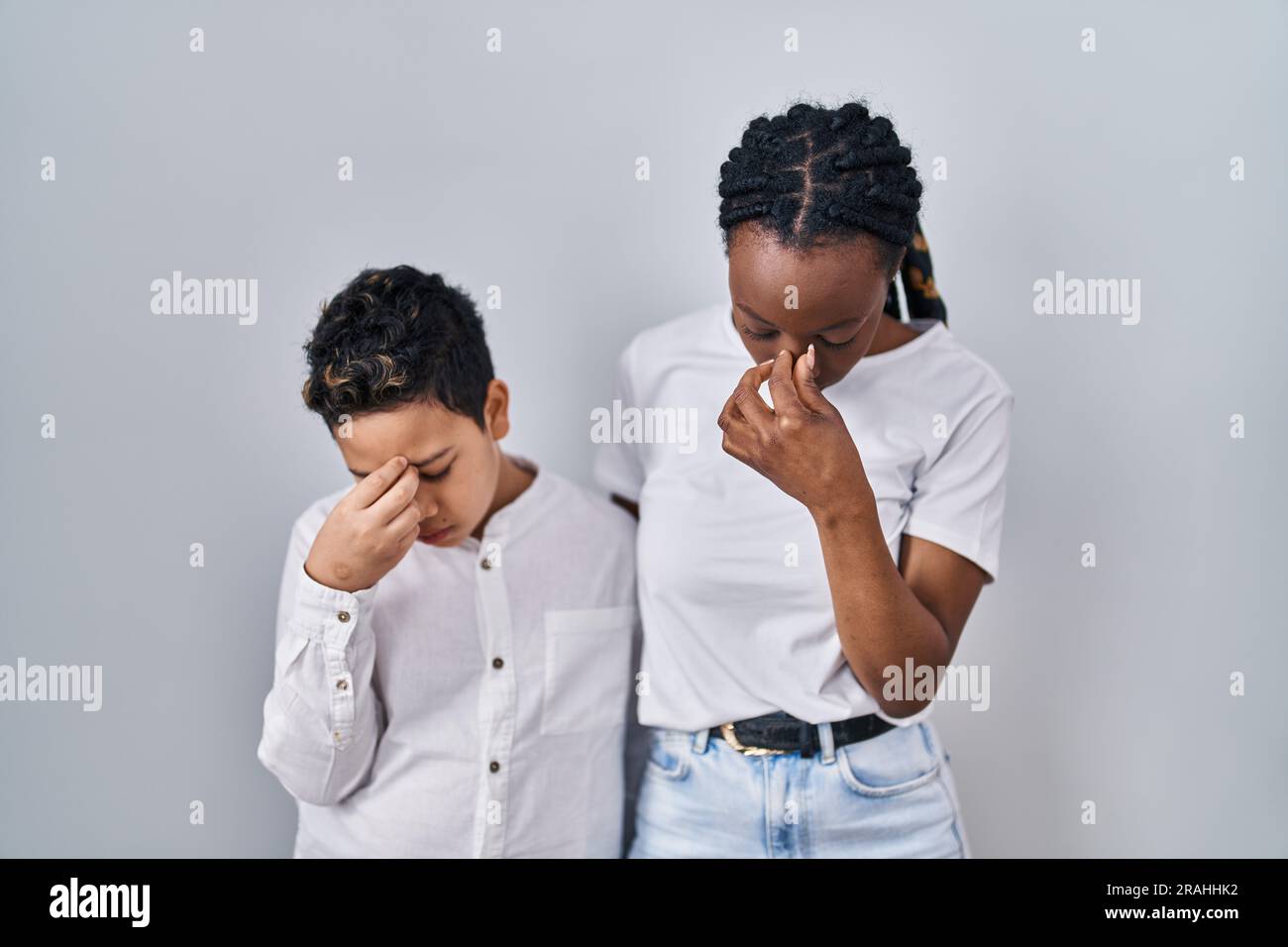 Young mother and son standing together over white background tired ...