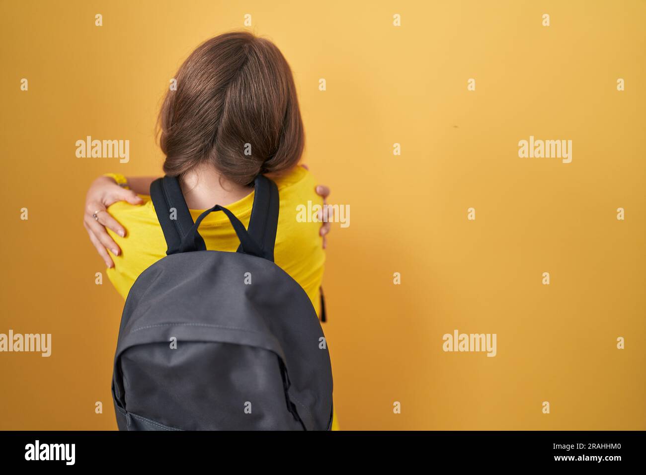 Young caucasian woman wearing student backpack over yellow background ...