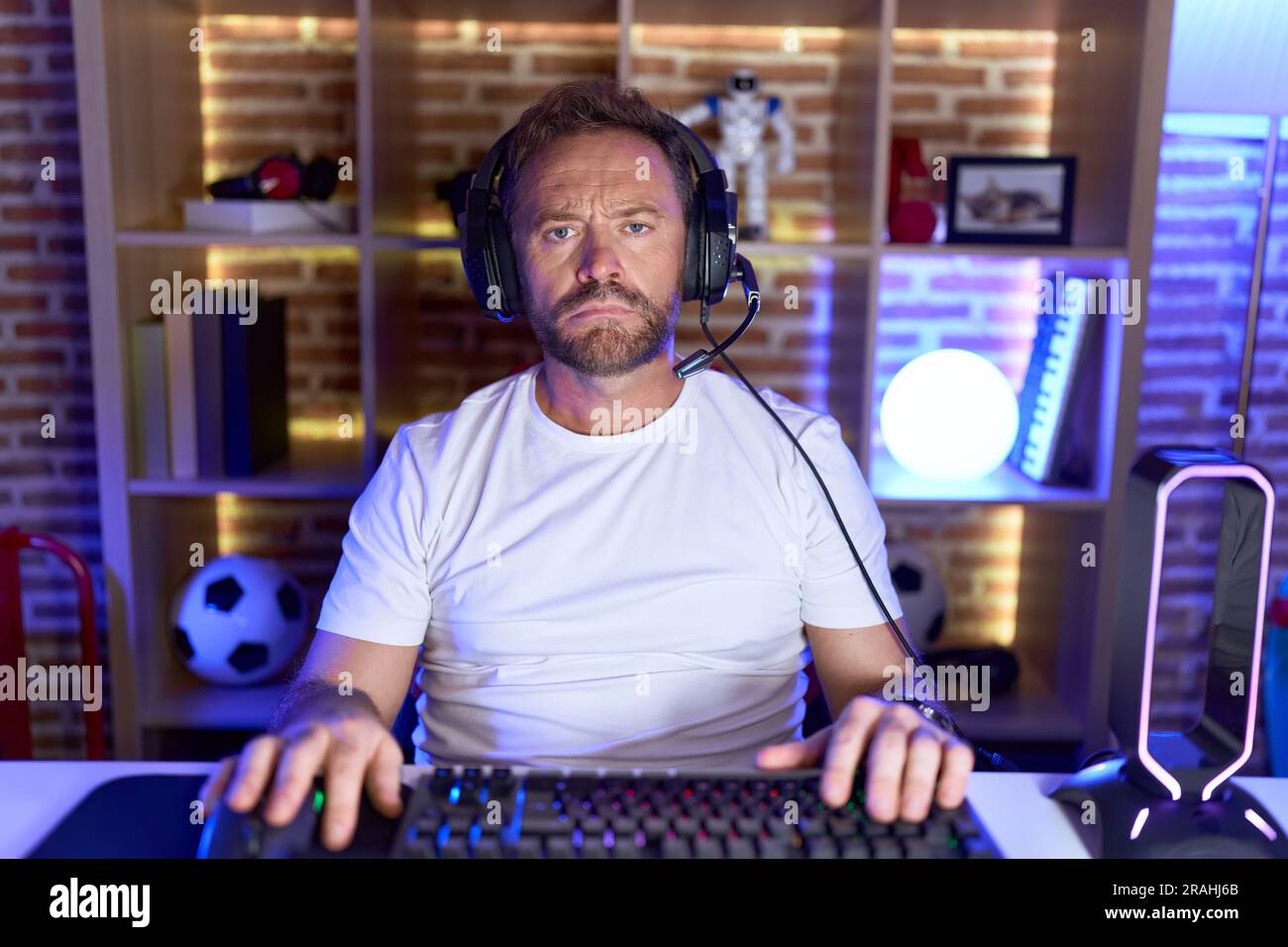 Middle age man with beard playing video games wearing headphones ...