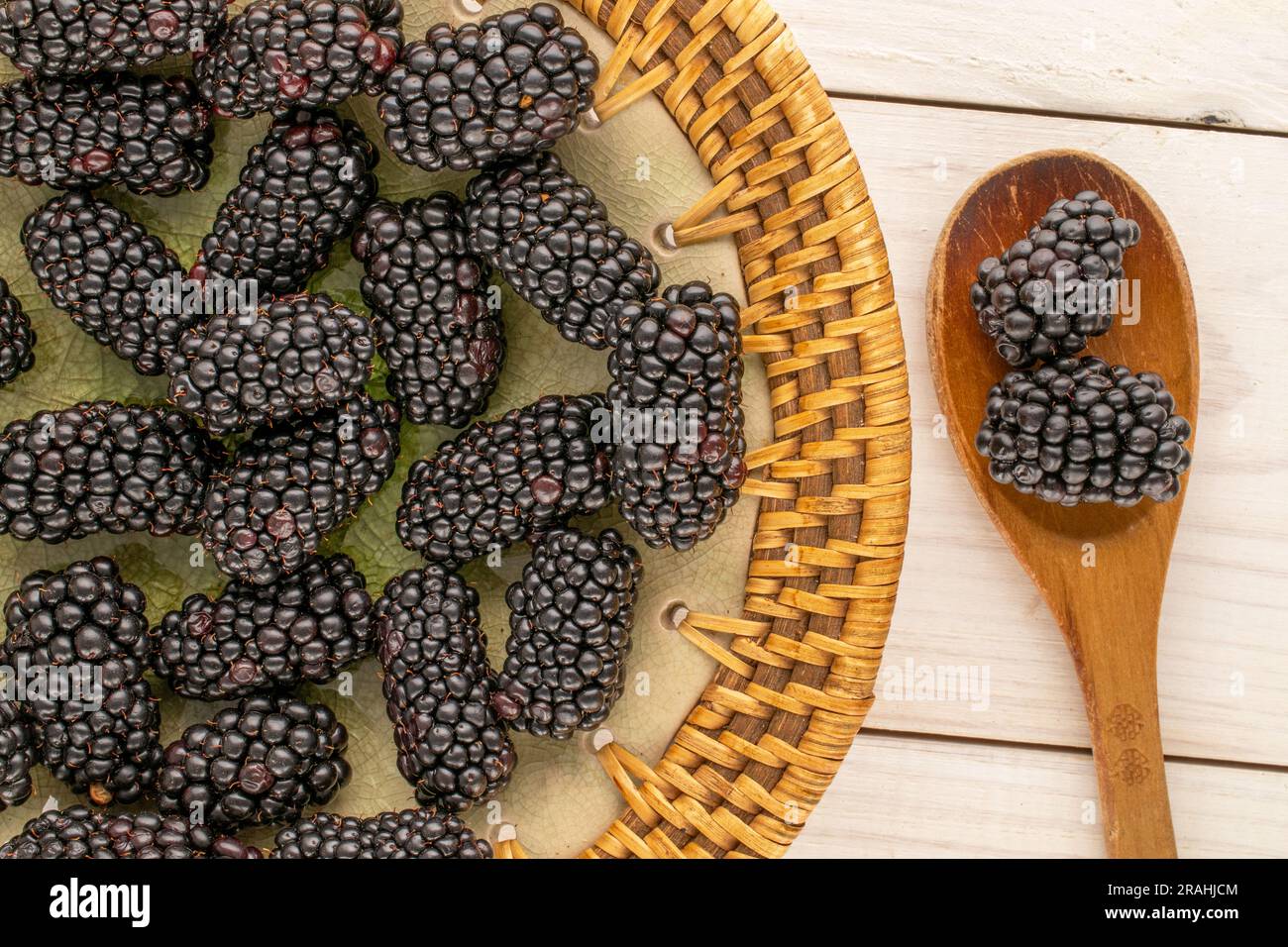 Several sweet blackberry berries with ceramic plate and wooden spoon on ...