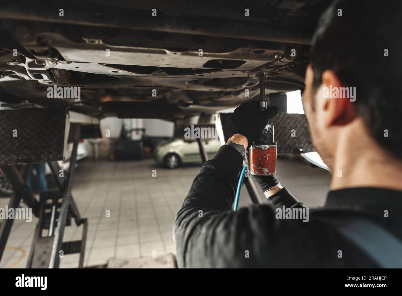 Workman mechanic working under car in auto repair shop Stock Photo - Alamy