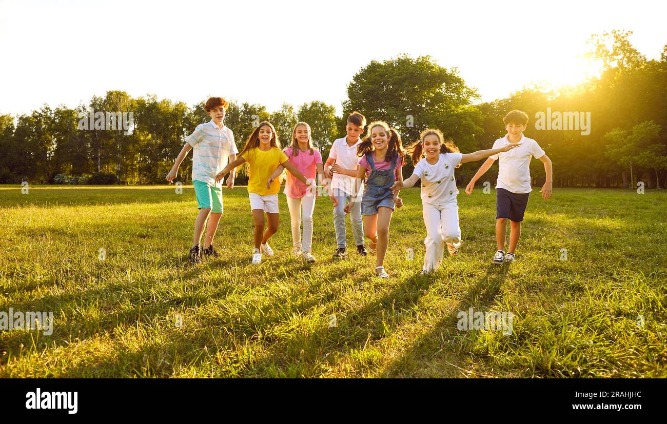 Happy children playing in the park in summer, running on green grass ...
