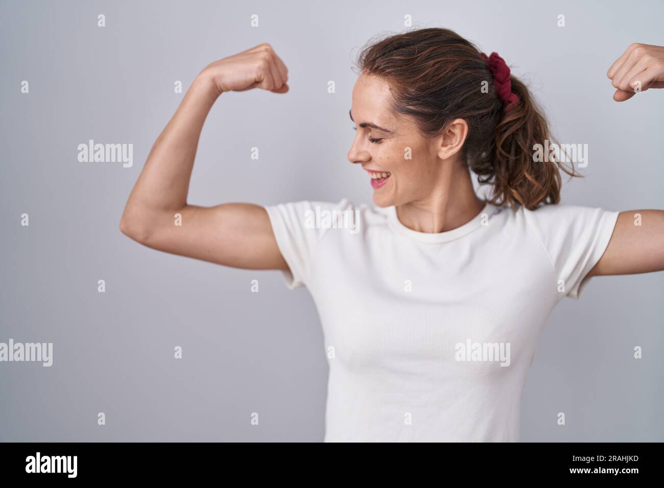 Beautiful brunette woman standing over isolated background showing arms ...