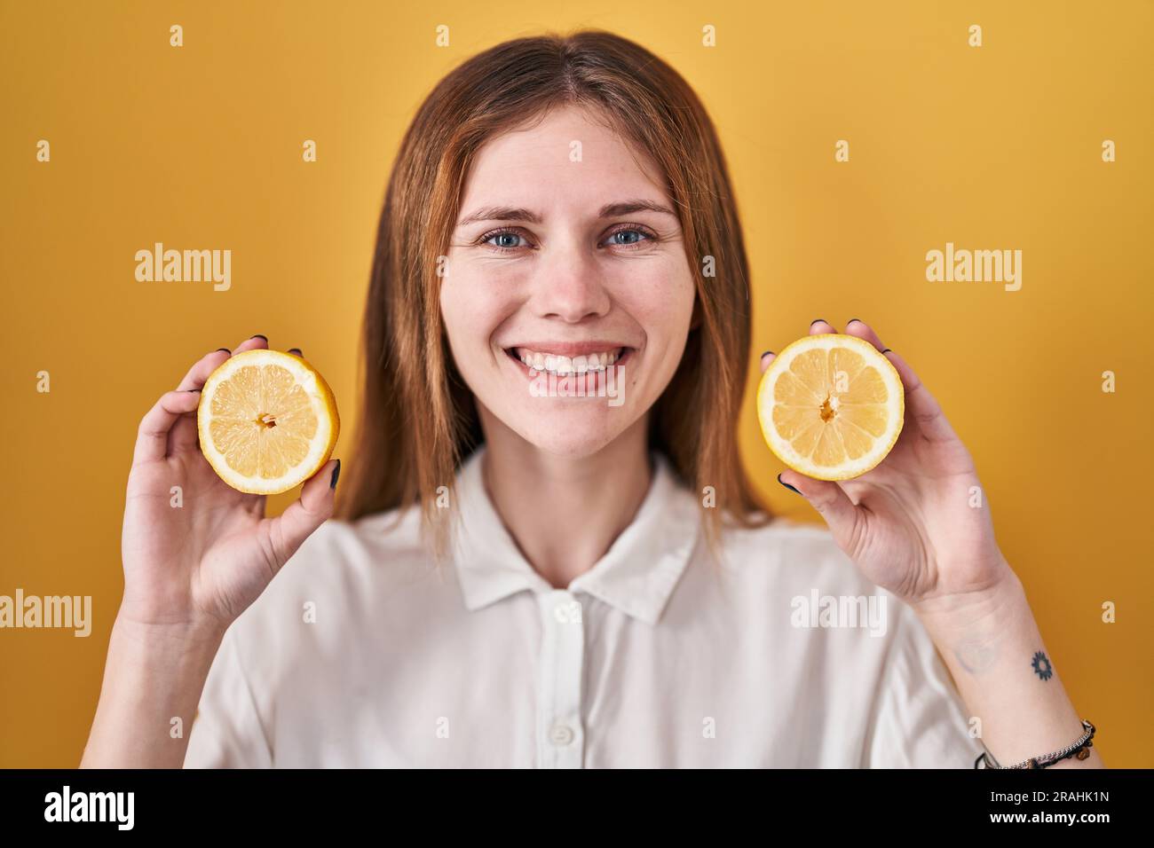 Beautiful woman holding lemons smiling with a happy and cool smile on ...
