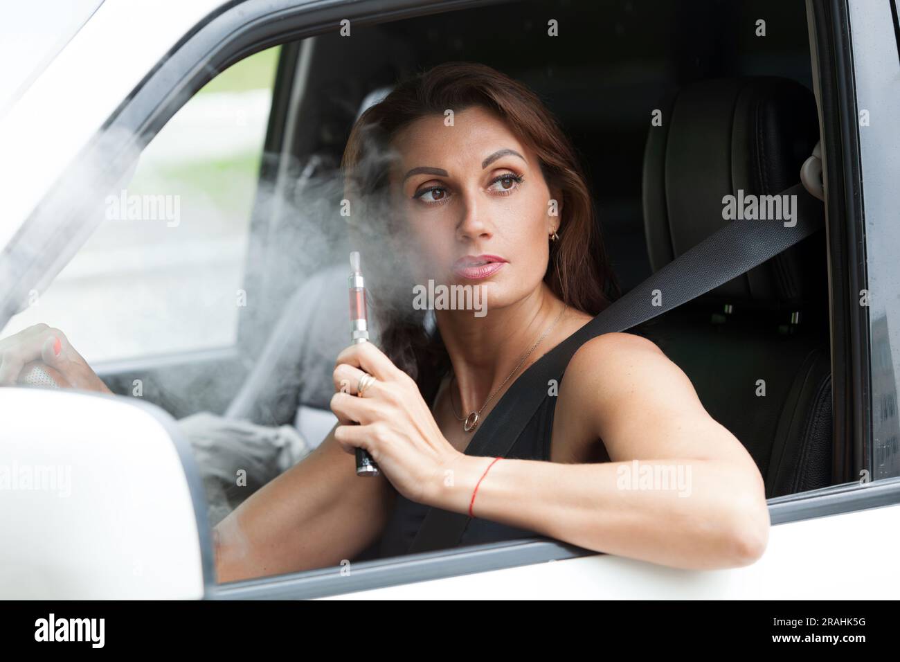 Young woman smoking electronic cigarette while driving a car Stock ...