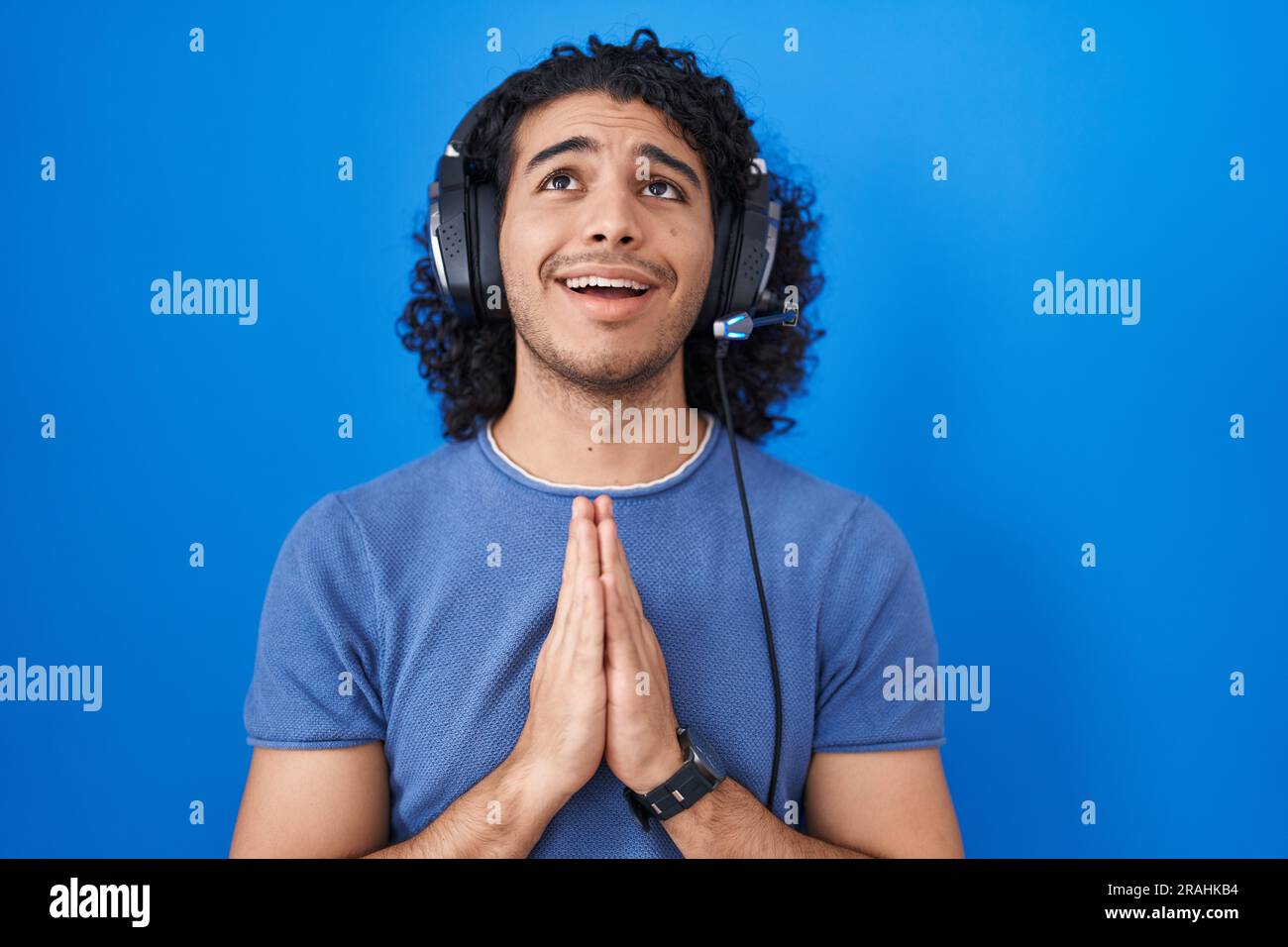 Hispanic man with curly hair listening to music using headphones ...