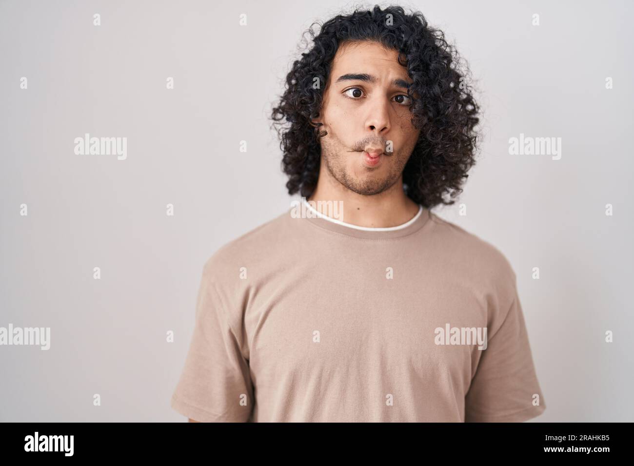Hispanic man with curly hair standing over white background making fish ...