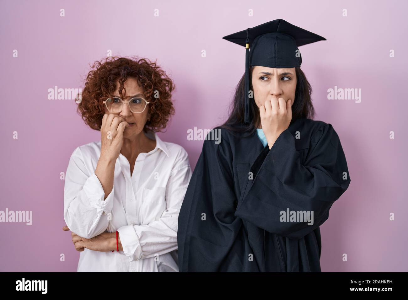 Hispanic mother and daughter wearing graduation cap and ceremony robe ...