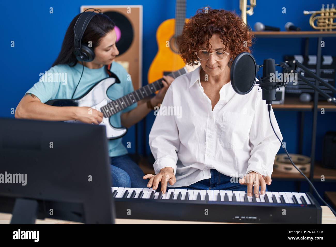 Two women musicians playing piano keyboard and electrical guitar at ...