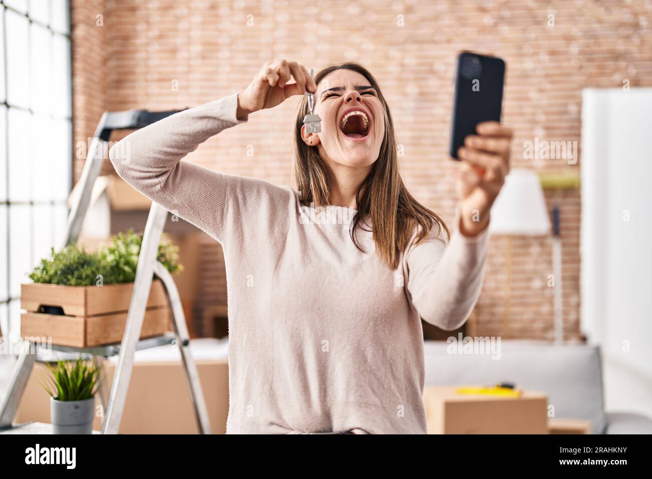 Beautiful woman holding keys of new home showing on video call angry ...